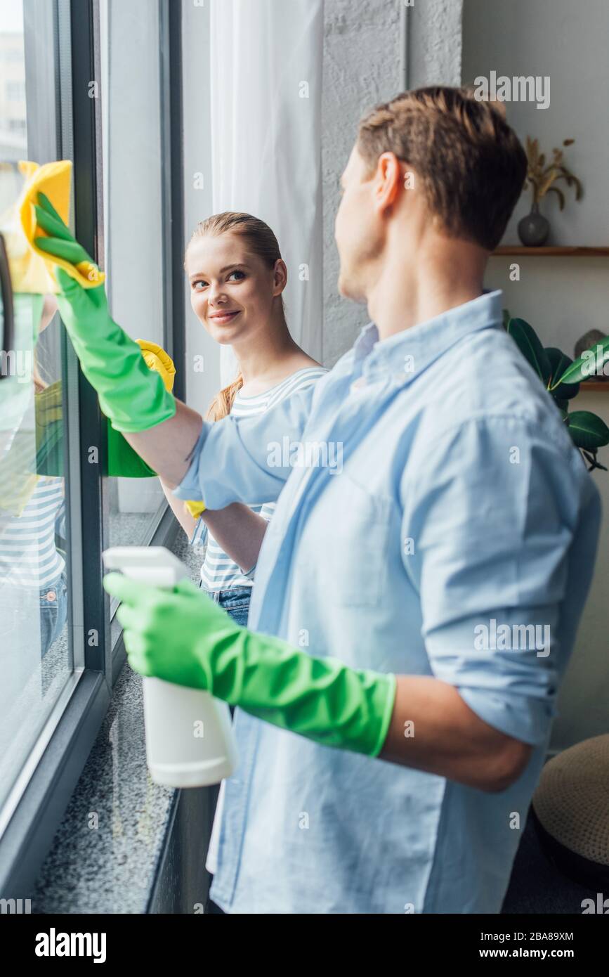 Side view of couple smiling at each other while cleaning glass of ...