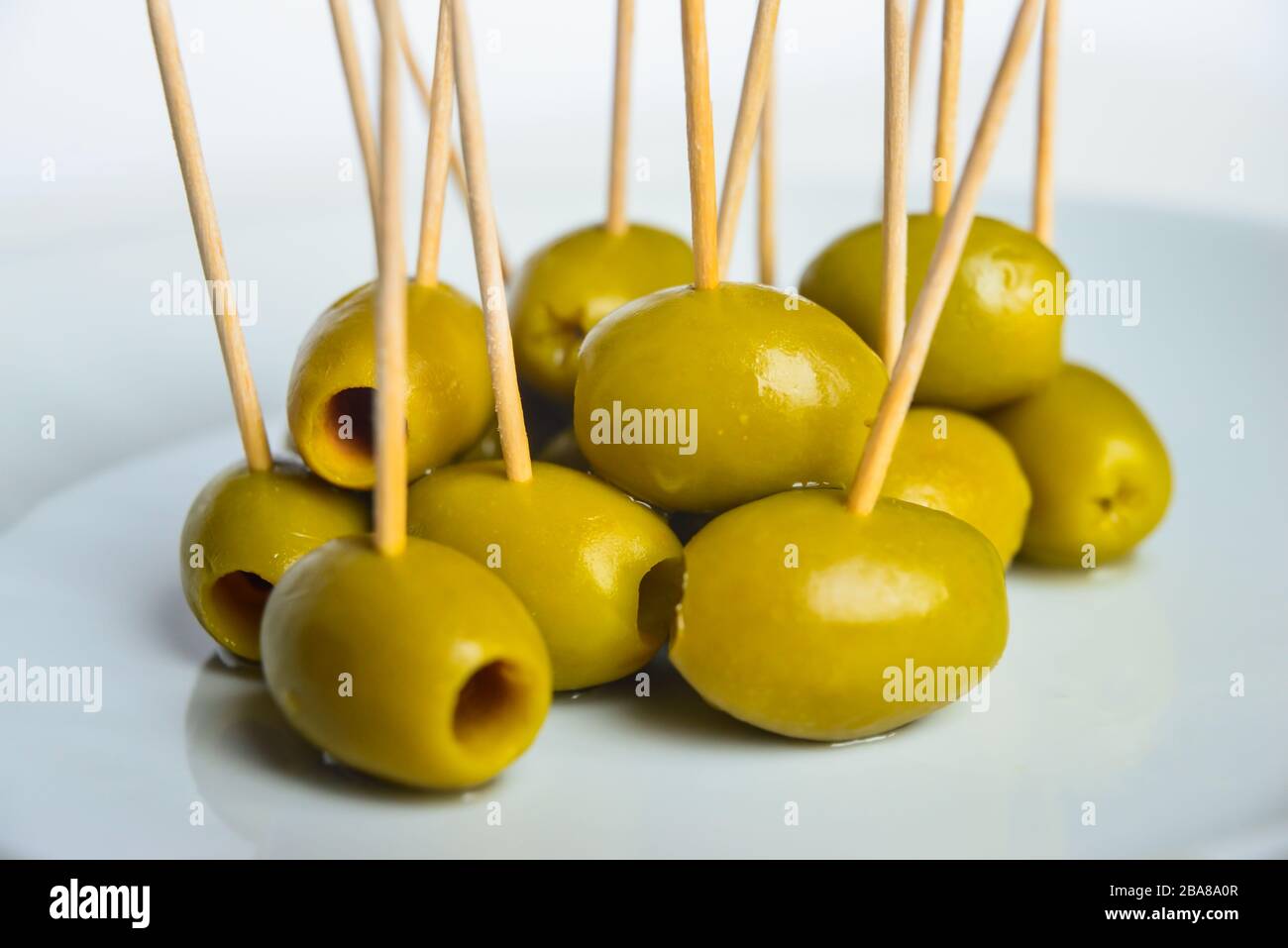 Pickled olives with toothpick on a white plate Stock Photo - Alamy