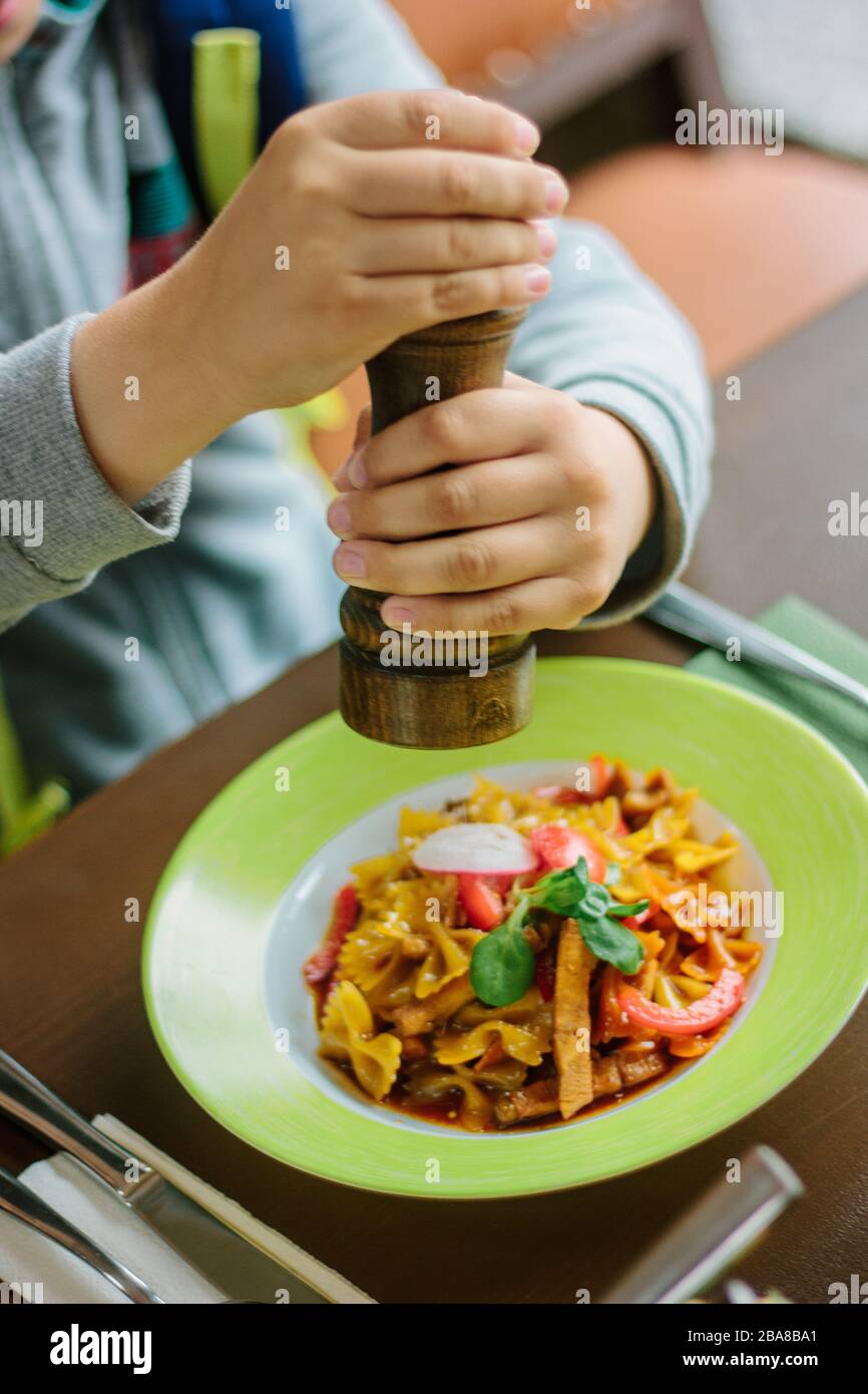 Kid hands and pepper grinder over the plate with food, great image for ...