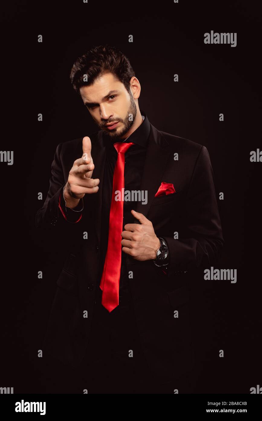 Handsome man in suit pointing with fingers and looking at camera ...