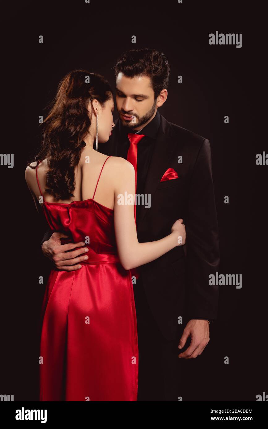 Handsome man in suit hugging by waist elegant girlfriend in red dress ...