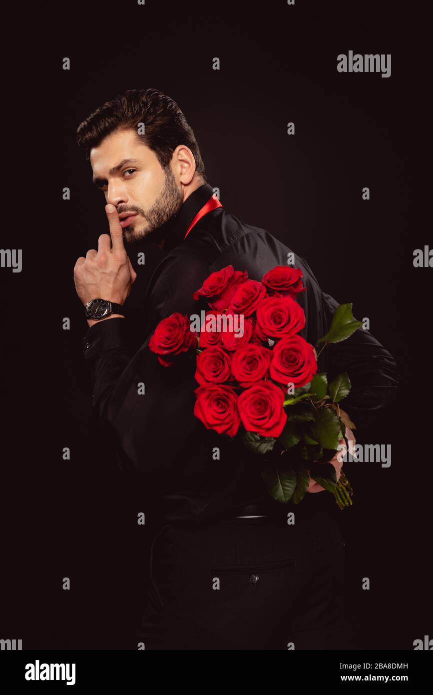 Side view of handsome man holding bouquet of roses and showing secret ...