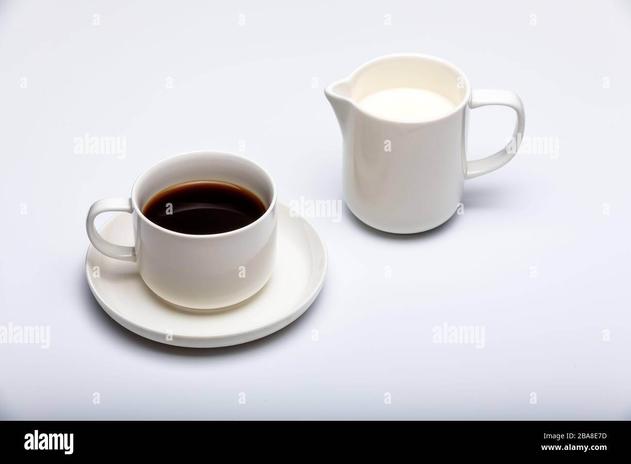 Creamer and cup of coffee on white background Stock Photo - Alamy