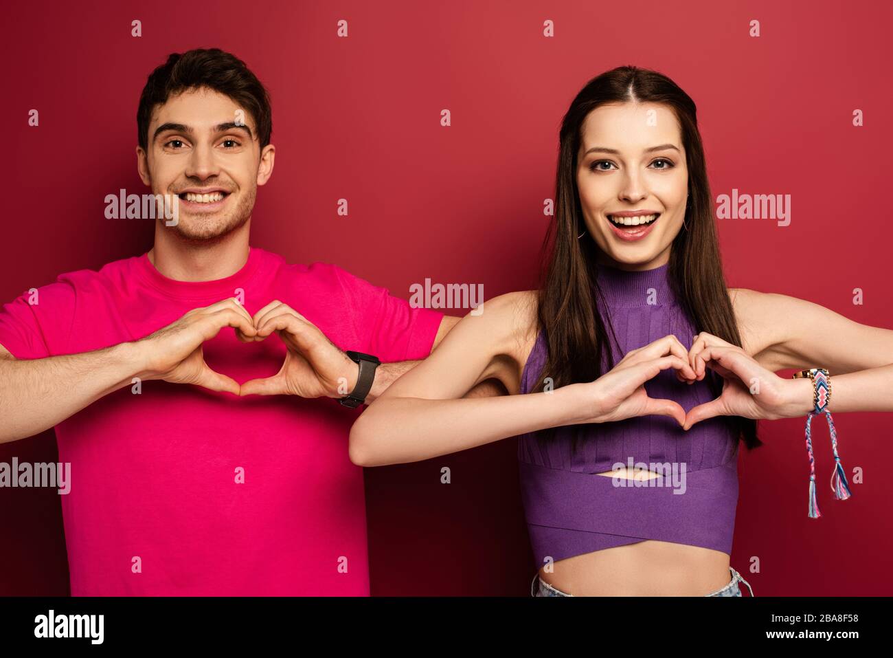 beautiful emotional young couple making heart signs with hands on red ...