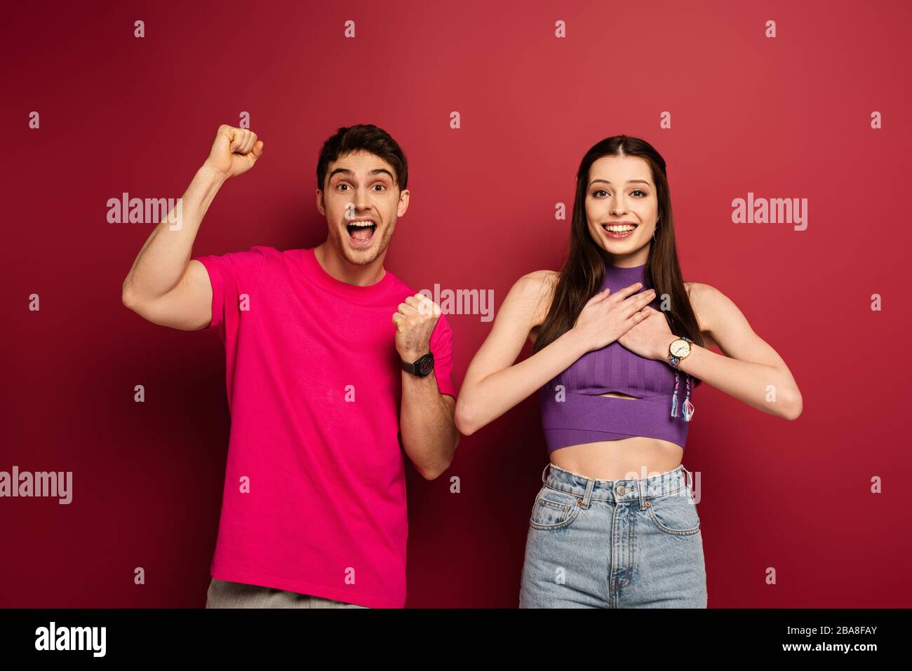 cheerful boyfriend and happy girlfriend with hand on heart on red Stock ...