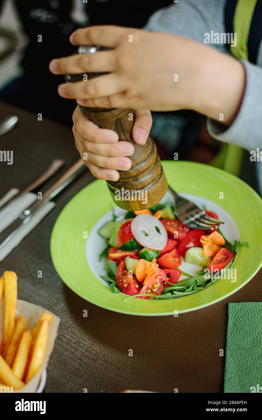 Kid hands and pepper grinder over the plate with food, great image for ...