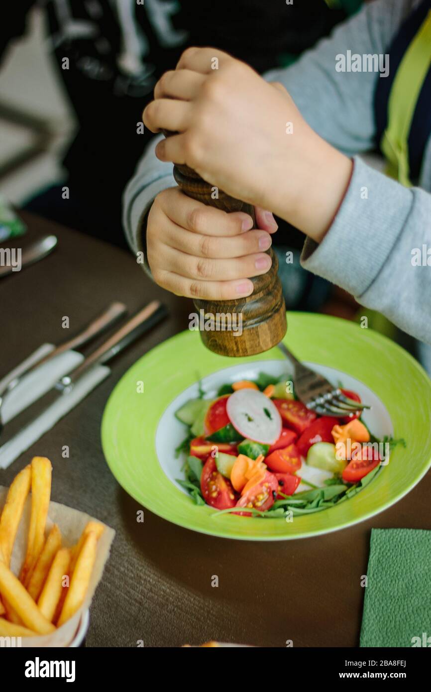 Kid hands and pepper grinder over the plate with food, great image for ...
