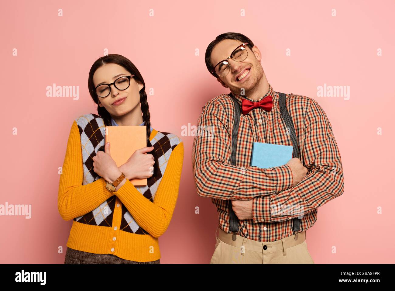 couple of cheerful nerds in eyeglasses hugging books on pink Stock ...