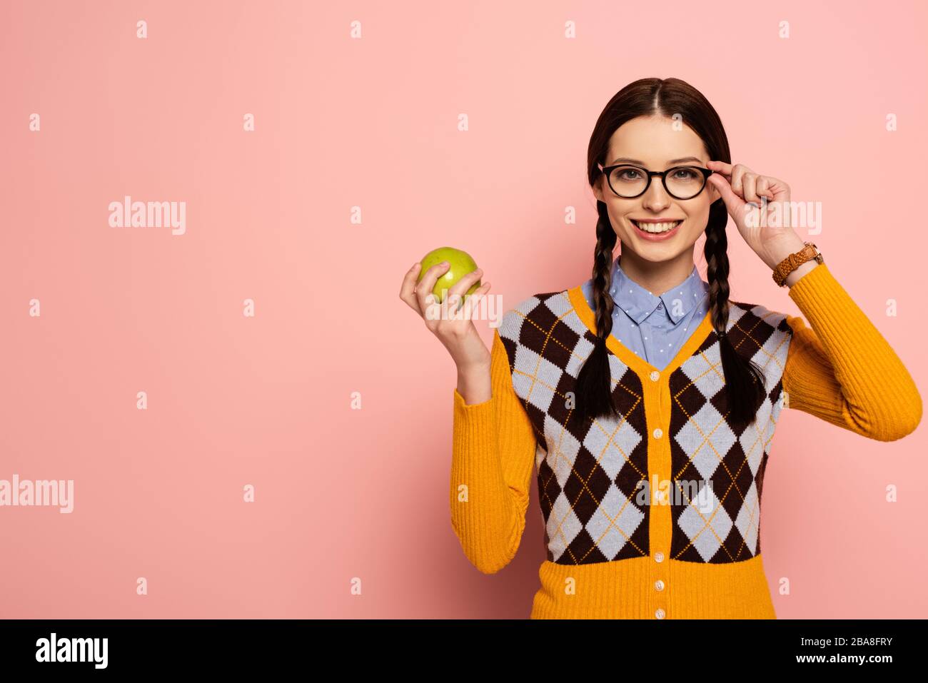 smiling female nerd in eyeglasses holding apple on pink Stock Photo - Alamy