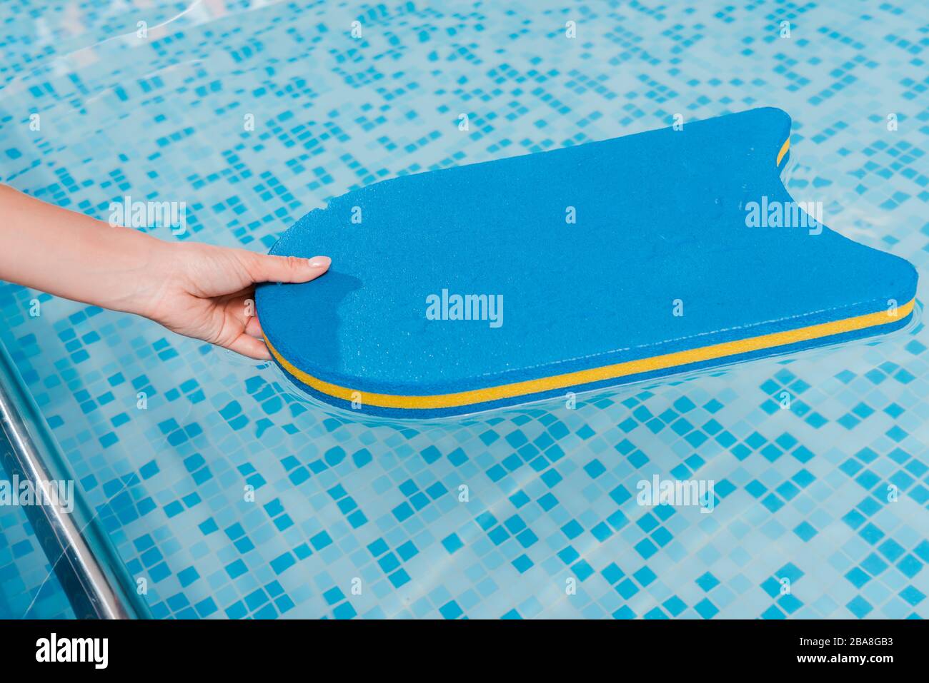 cropped view of woman touching flutter board in swimming pool Stock ...