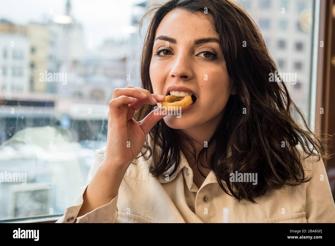 Beautiful young cute girl in fashionable clothes fast food fried onion ...