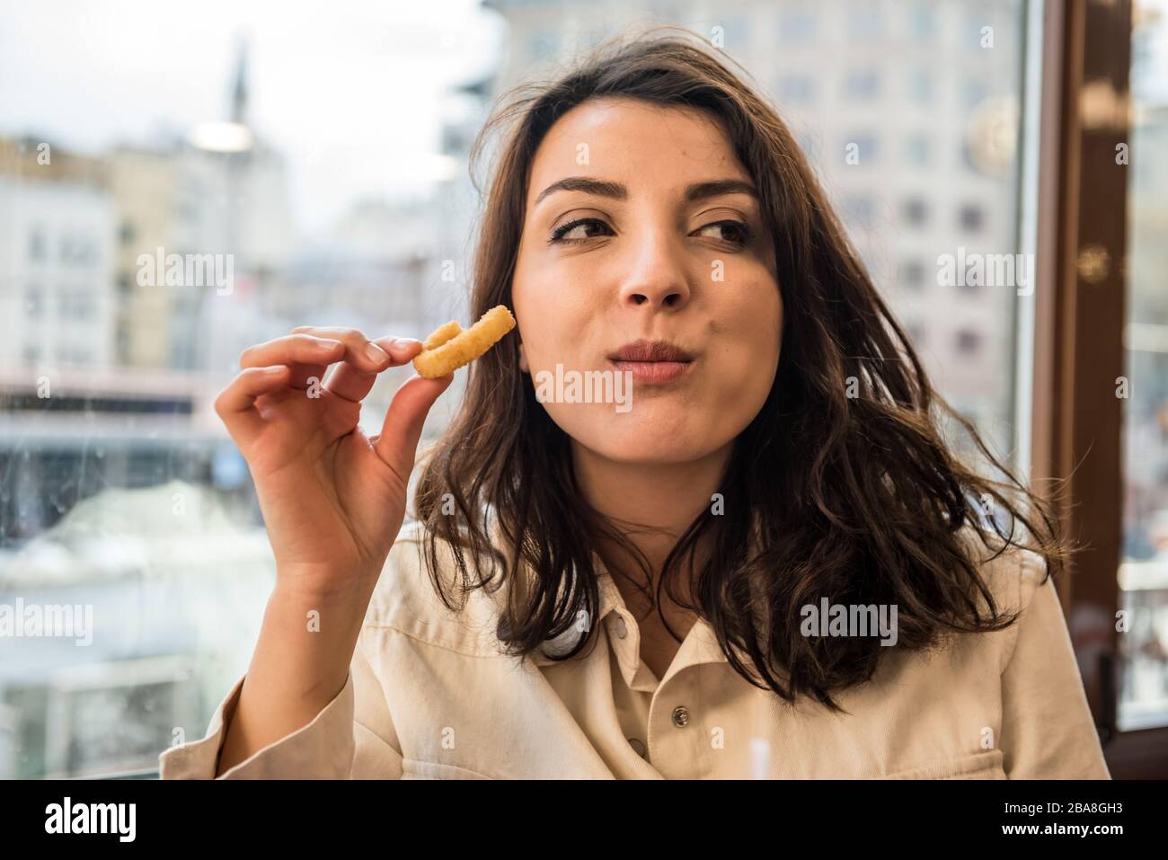 Beautiful young cute girl in fashionable clothes fast food fried onion ...