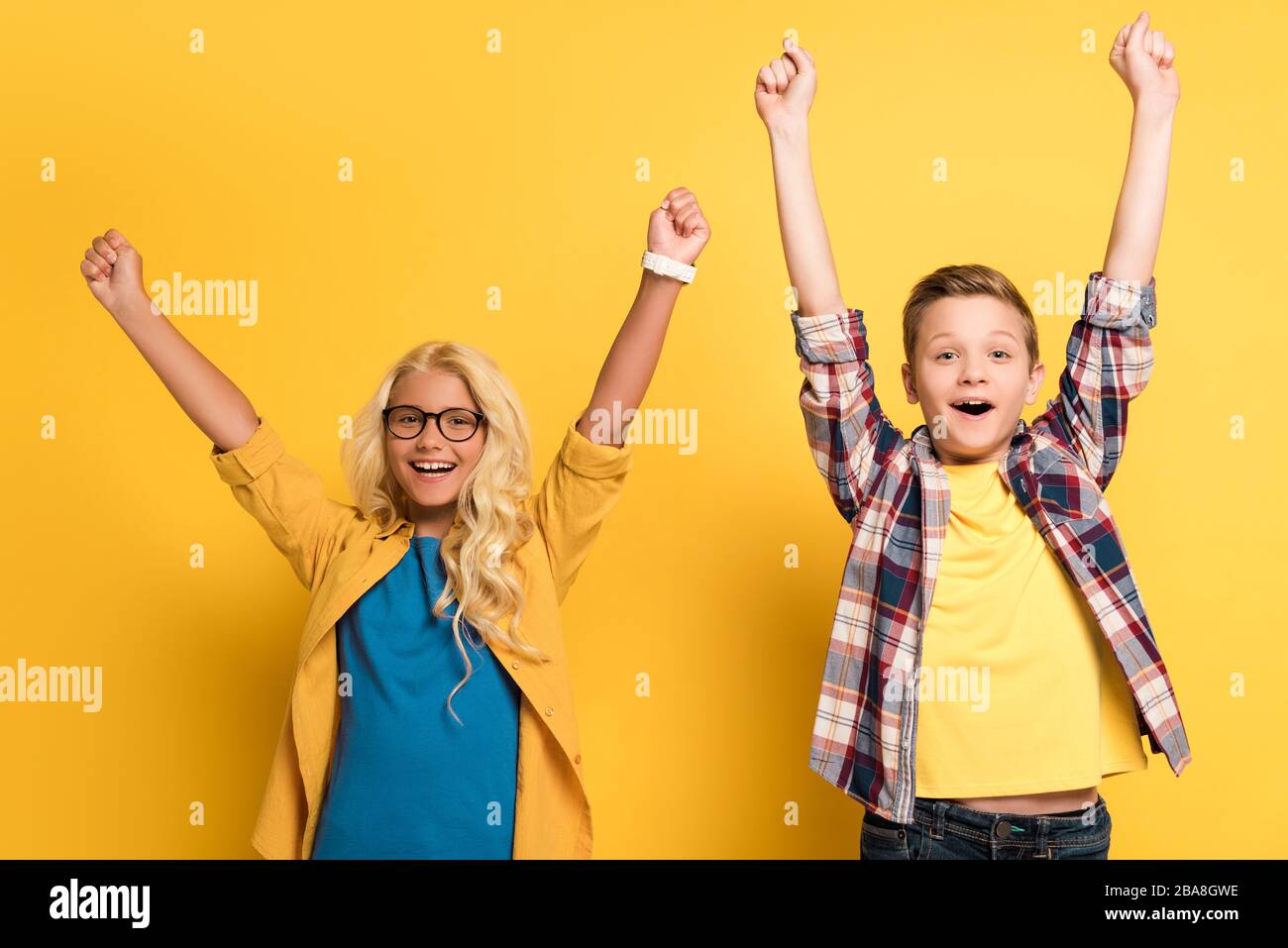 smiling kids showing yes gesture and looking at camera on yellow ...