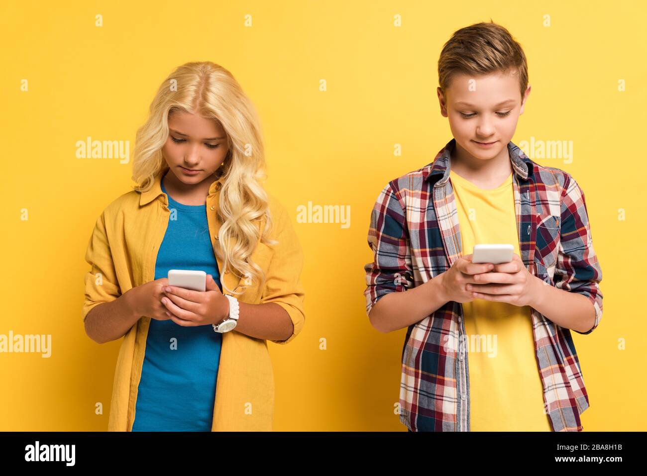 smiling and cute kids using smartphones on yellow background Stock ...