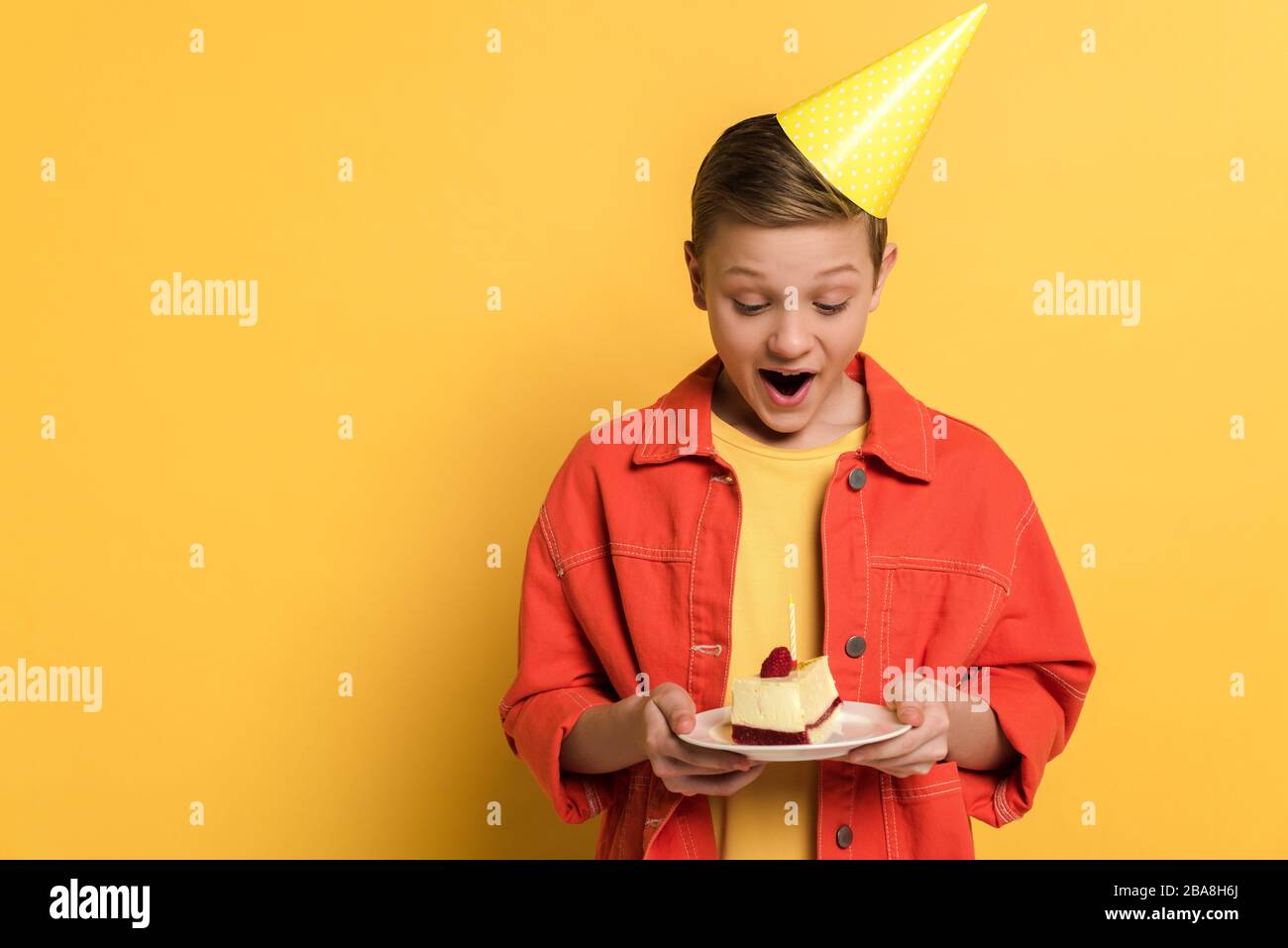 shocked kid holding plate with birthday cake on yellow background Stock ...