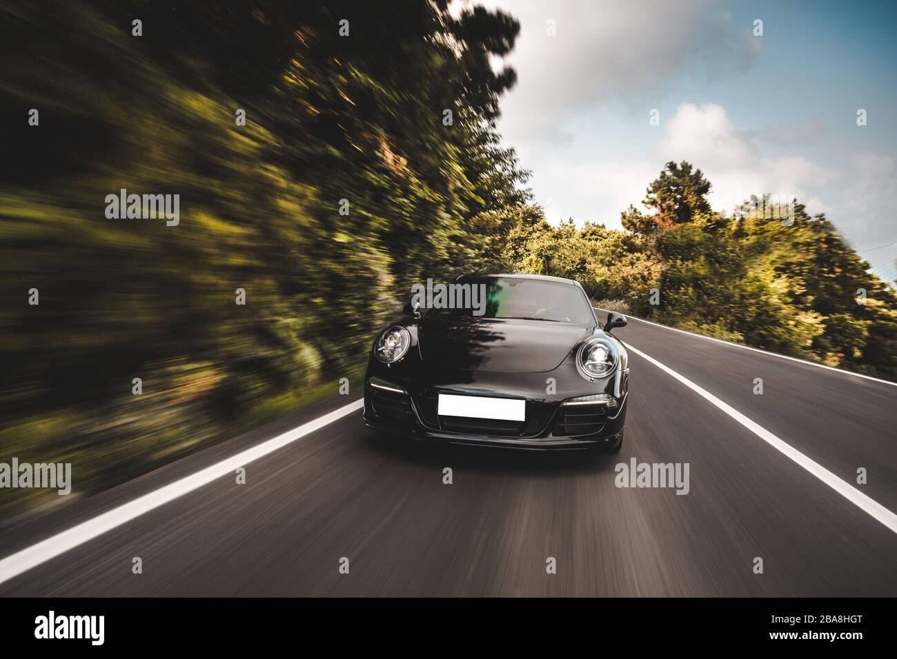 Black sedan driving in the forest road, front view Stock Photo - Alamy