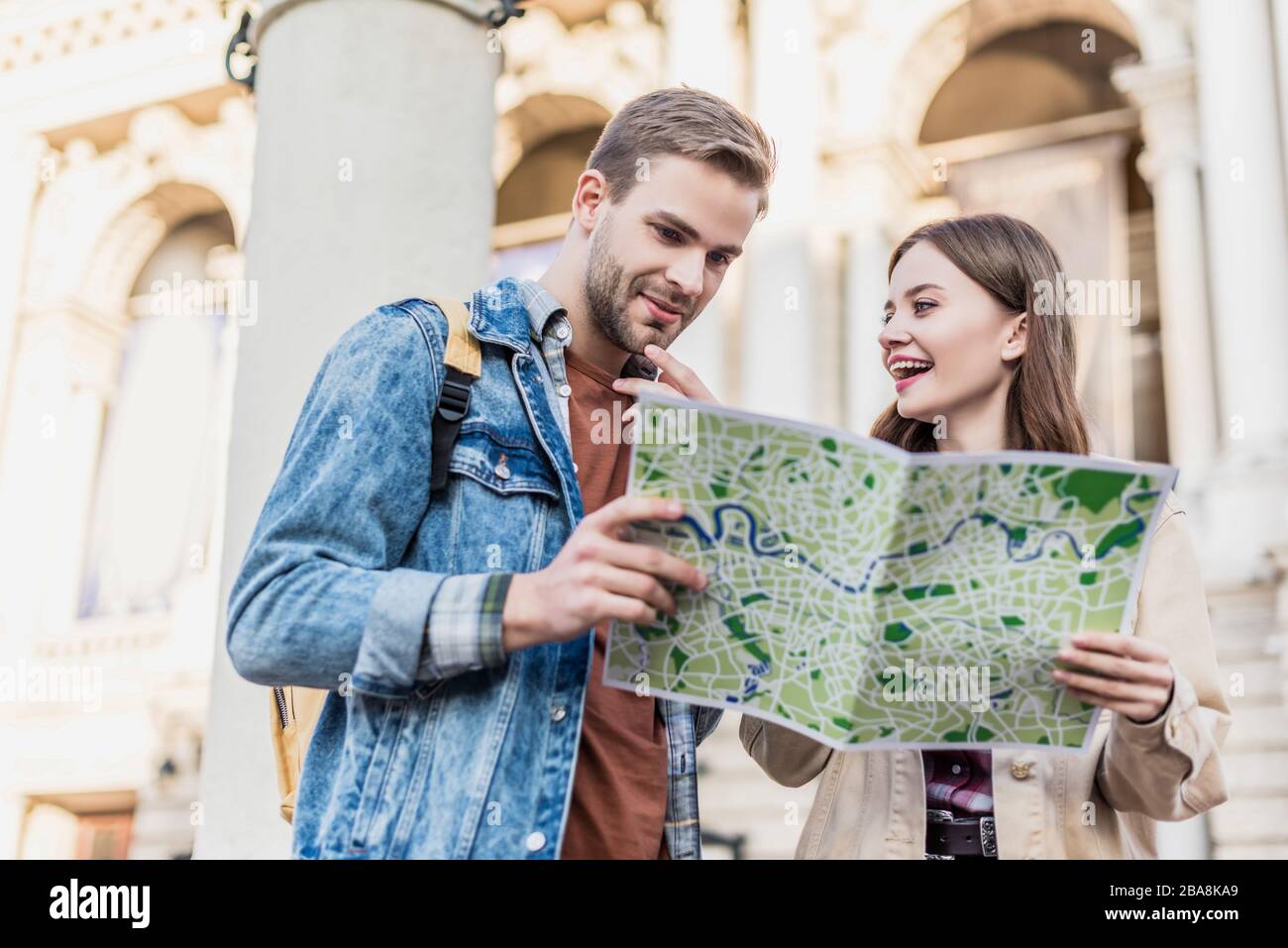 Low angle view of thoughtful boyfriend and happy girlfriend with map in ...