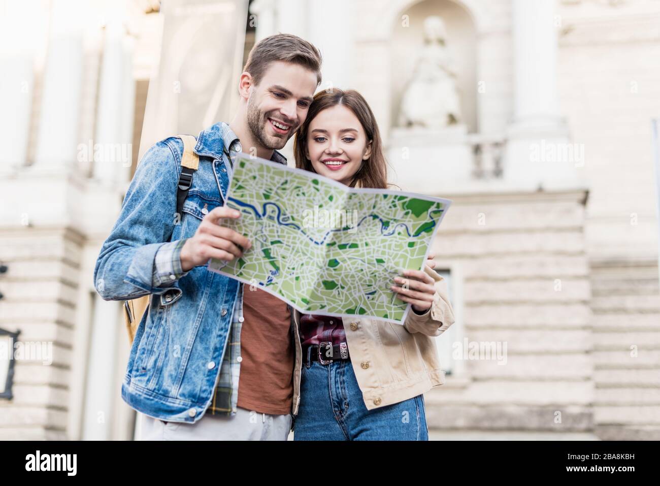 Couple looking at map together and smiling in city Stock Photo - Alamy