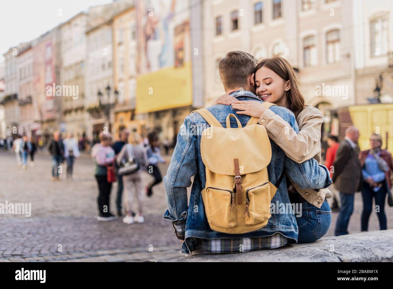 Boyfriend with backpack and girlfriend with closed eyes hugging and ...
