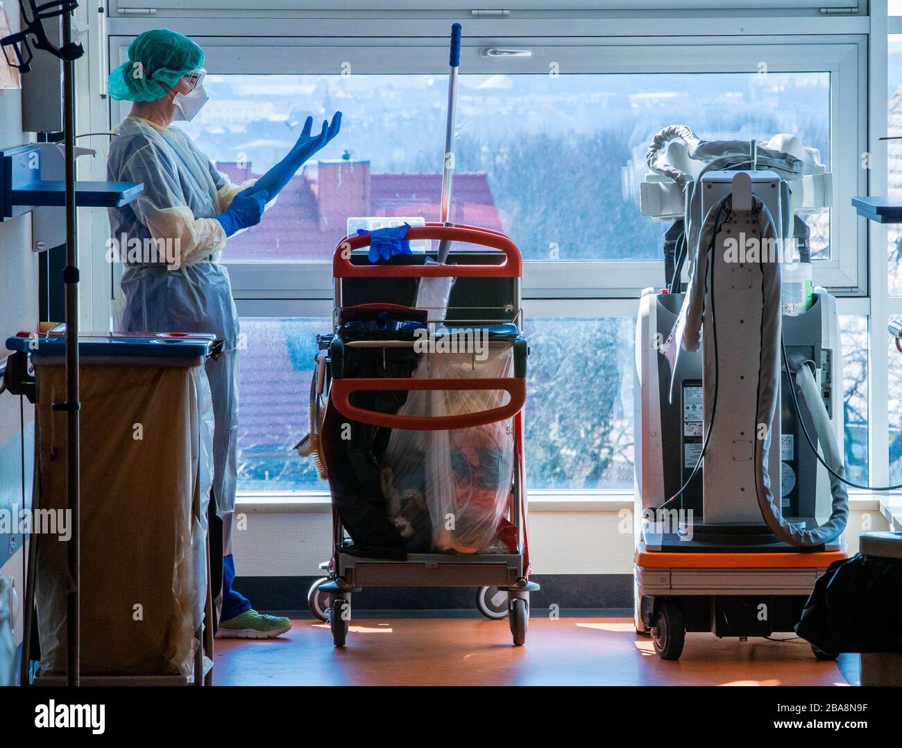 Schwerin, Germany. 26th Mar, 2020. An employee puts on her protective ...