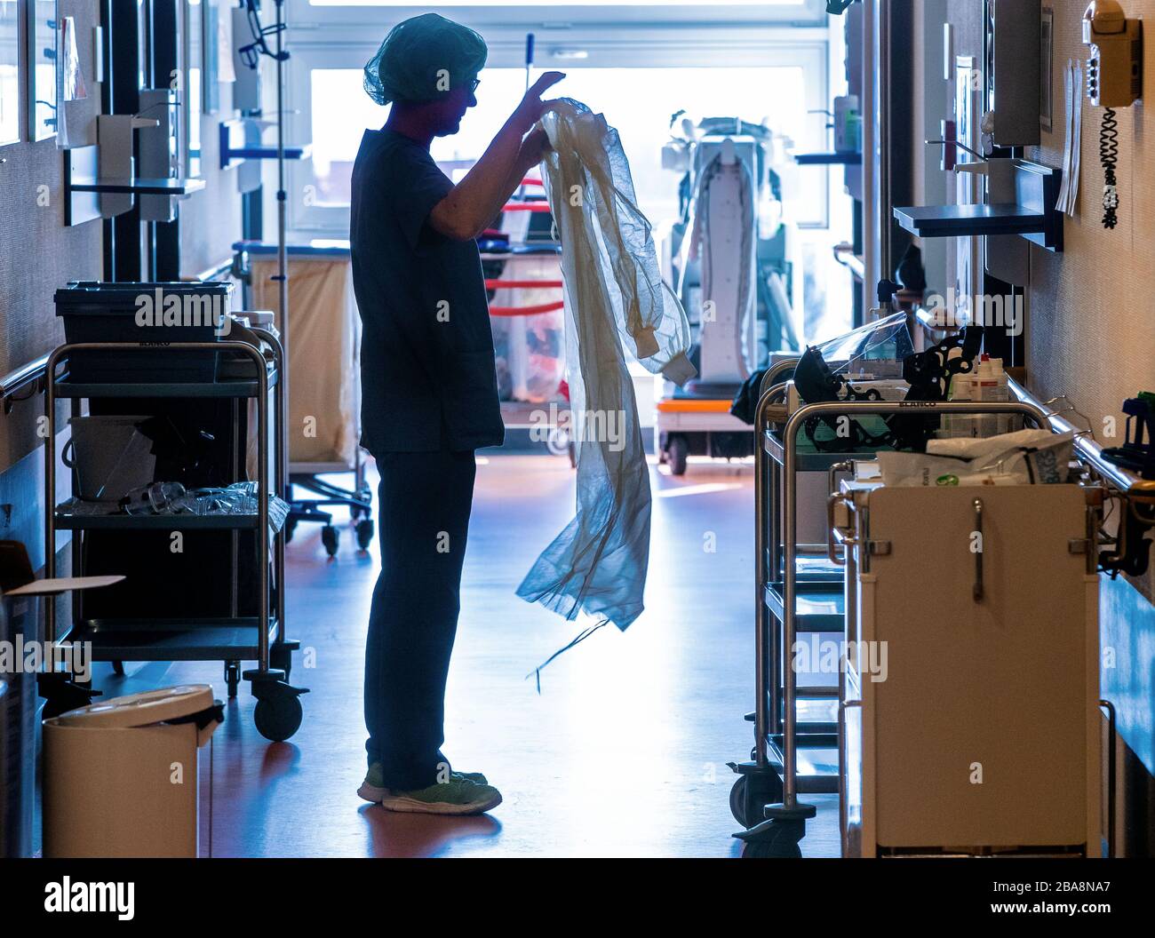 Schwerin, Germany. 26th Mar, 2020. A nurse puts on her protective ...