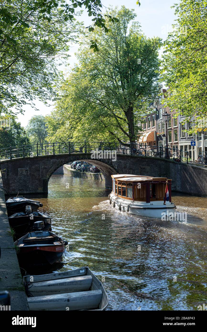 A canal boat approaches a bridge in Amsterdam, North Holland ...