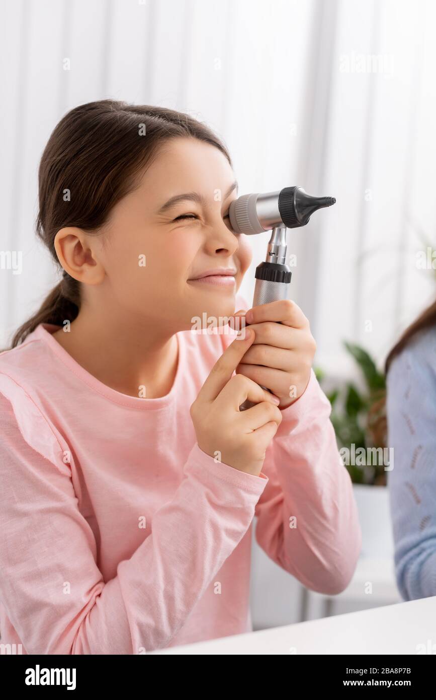 cute child smiling while looking through otoscope in clinic Stock Photo ...
