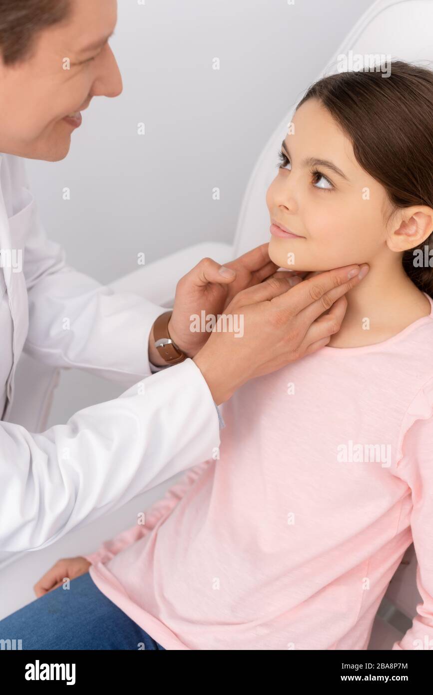 smiling ent physician touching neck of cute child while examining her ...