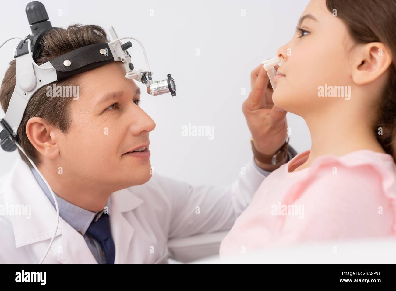 selective focus of attentive ent physician examining nose of cute child ...