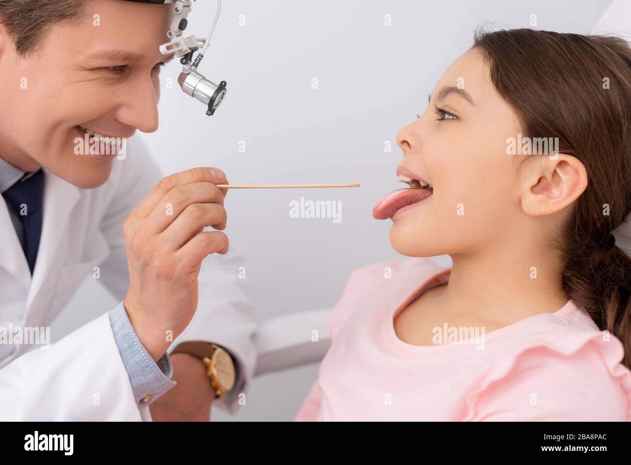 smiling ent physician examining throat of cute child with tongue ...