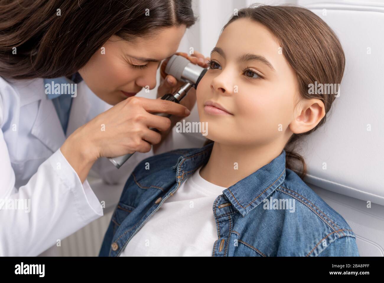 attentive otolaryngologist examining ear of adorable smiling child with ...