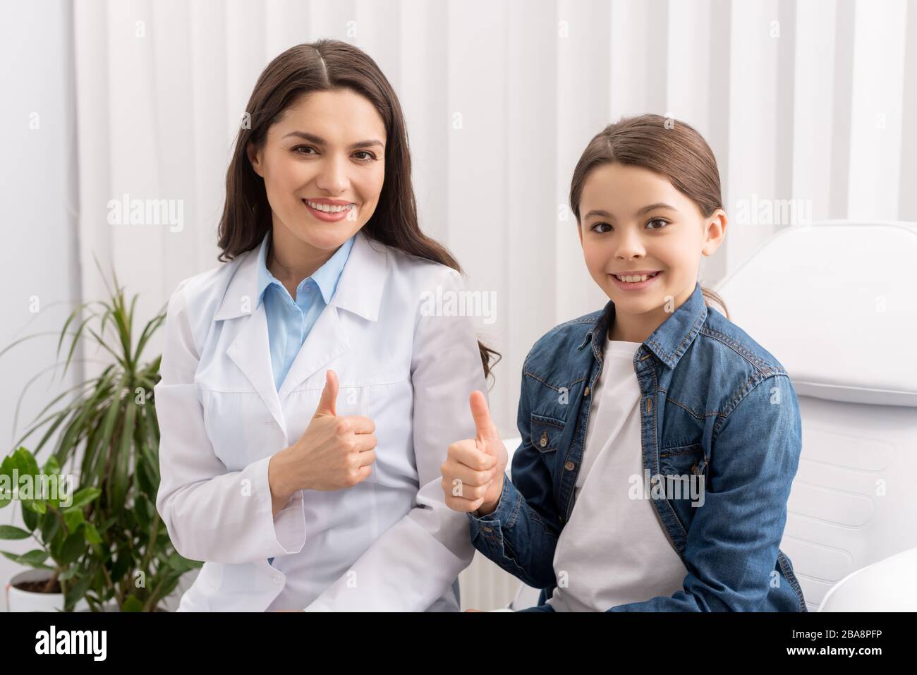 happy ent physician and child showing thumbs up while smiling at camera ...