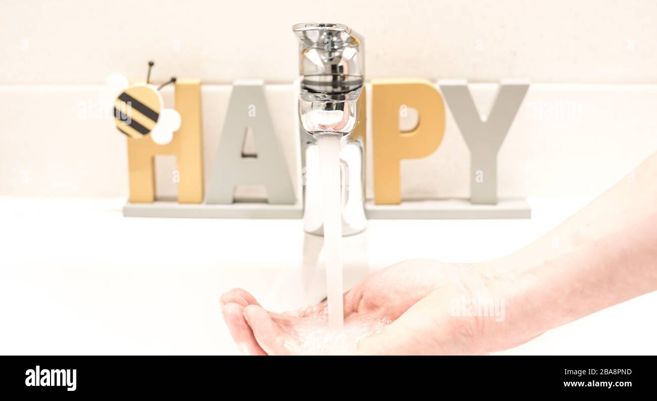 Fresh water from the tap landing on a hand - happy sign behind the tap ...