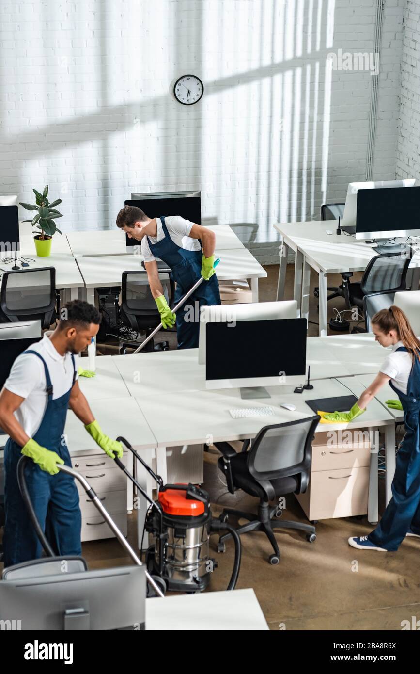 multicultural team of cleaners working in modern open space office ...