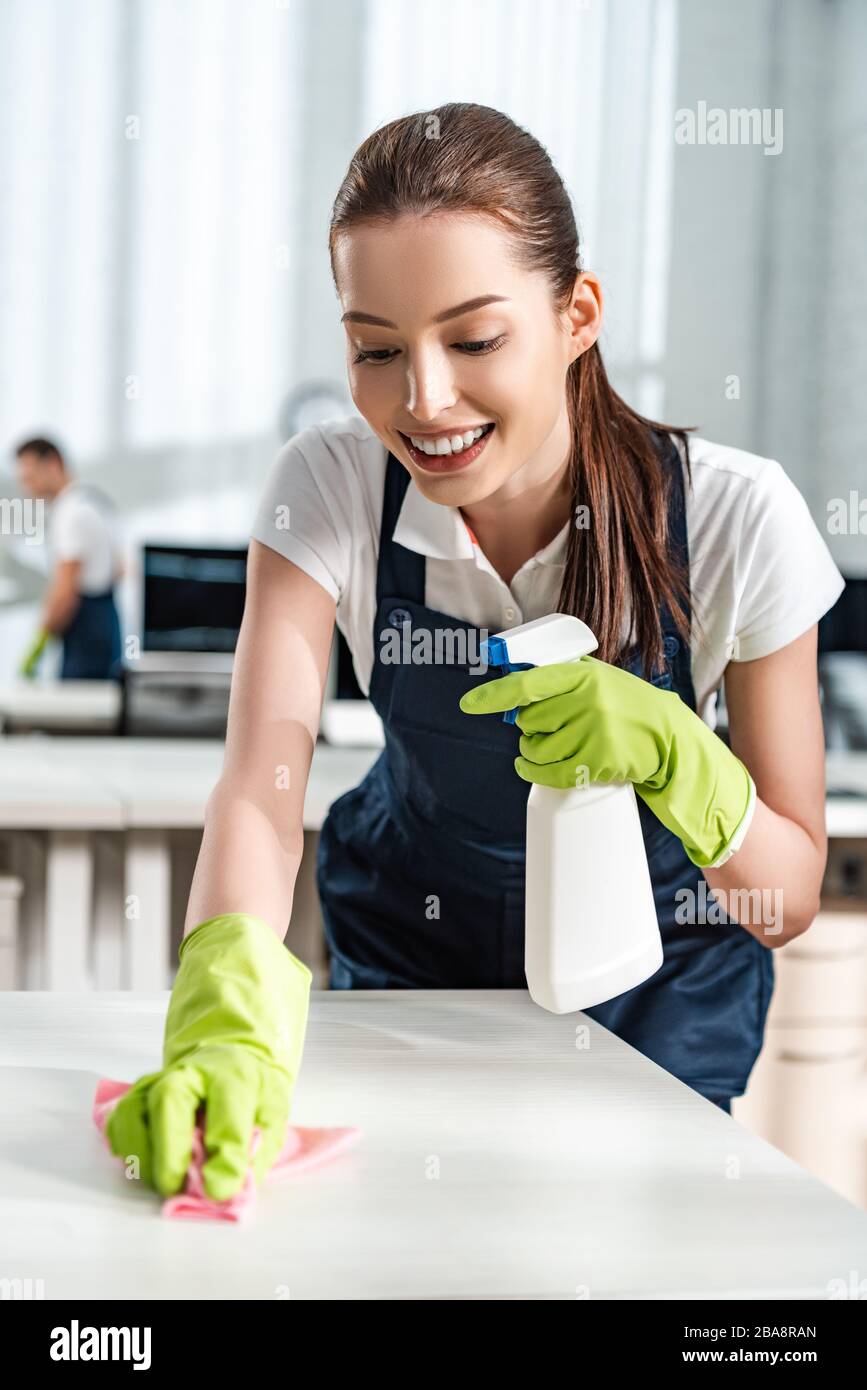 happy cleaner holding spray bottle while washing desk with rag Stock ...