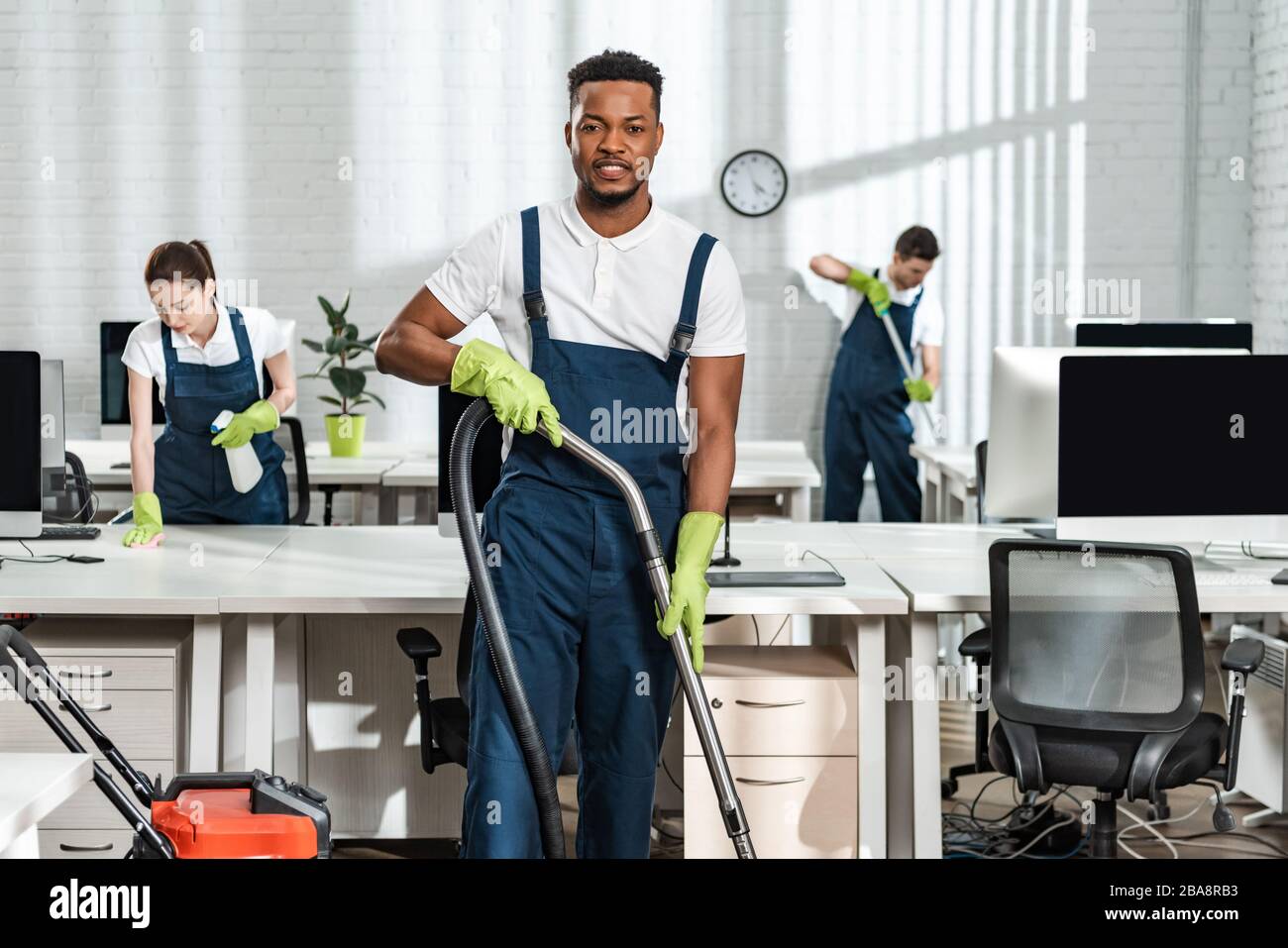 handsome african american cleaner looking at camera while standing with ...