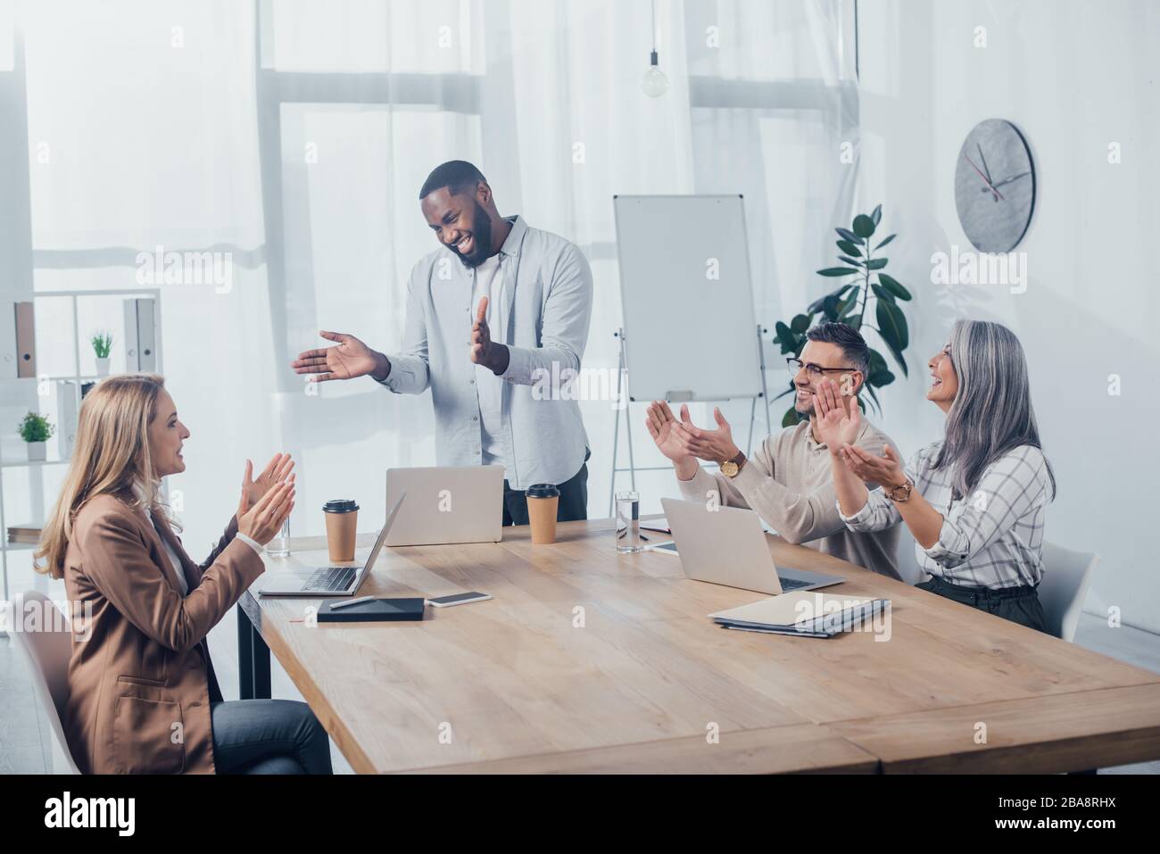 smiling multicultural colleagues clapping during meeting in creative ...