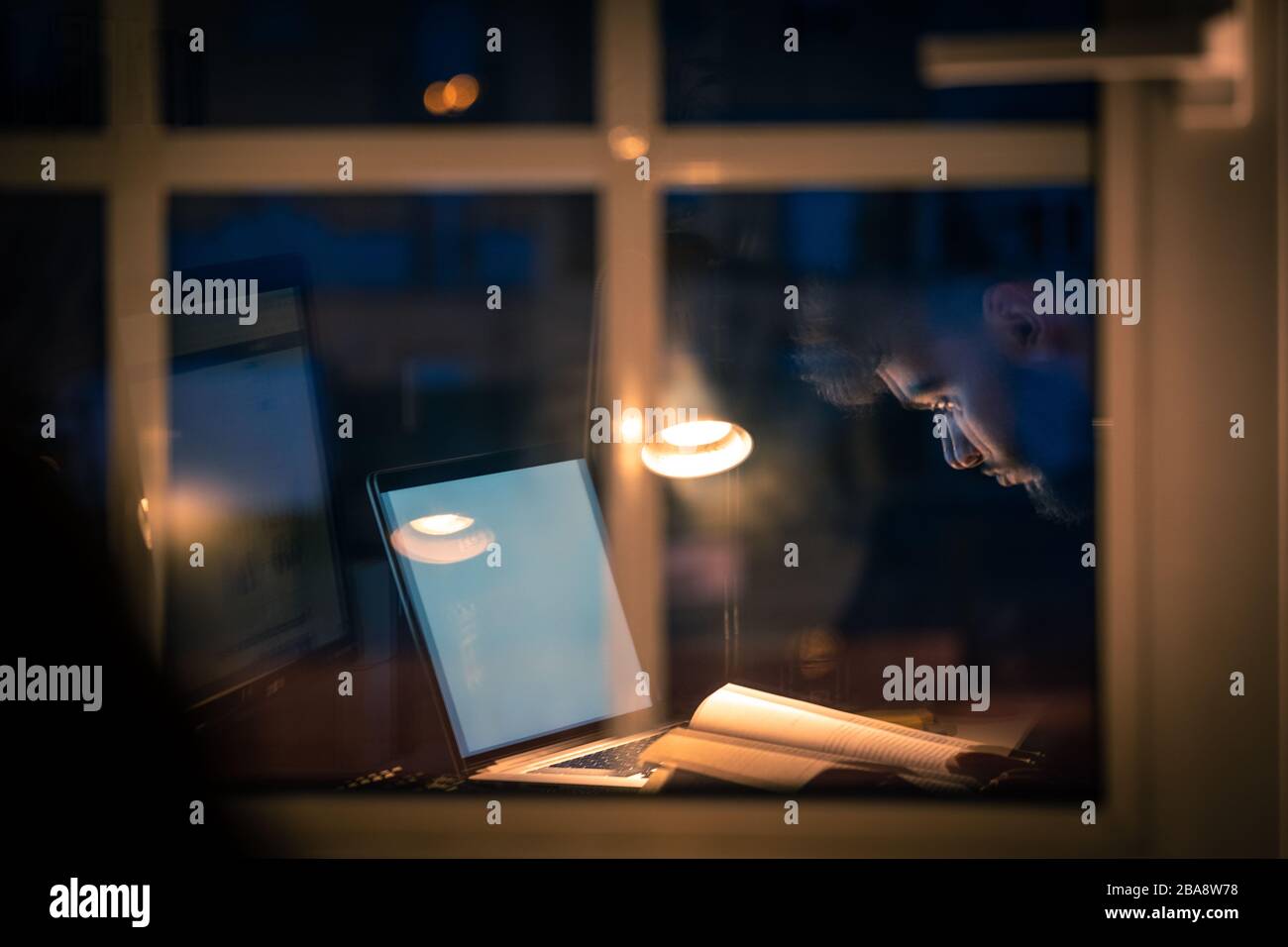 Person reading a book at night, reflection of the window Stock Photo ...