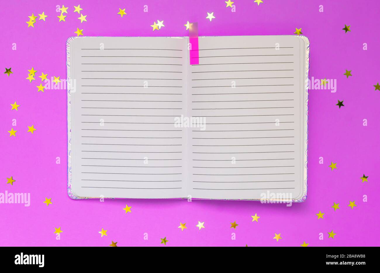 Open empty notebook on a pink background with stars confetti. Top view. Space for text or design ...