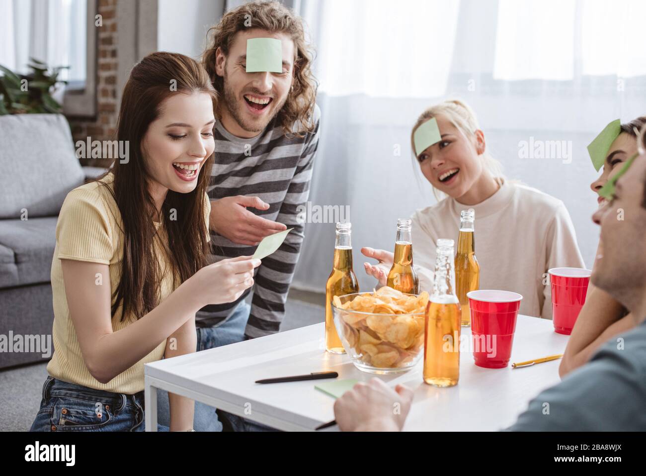 cheerful girl looking at sticky note while playing name game with happy ...