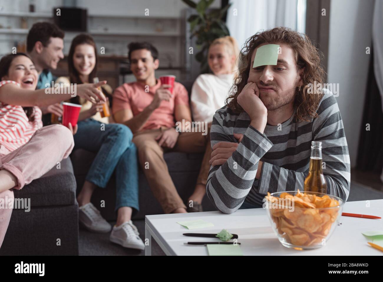 cheerful girl pointing with hand at bored man with sticky note on ...