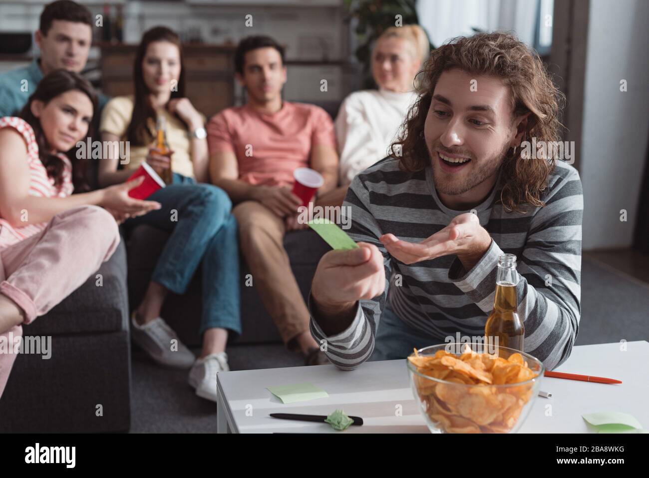selective focus of smiling man holding sticky note while playing name ...