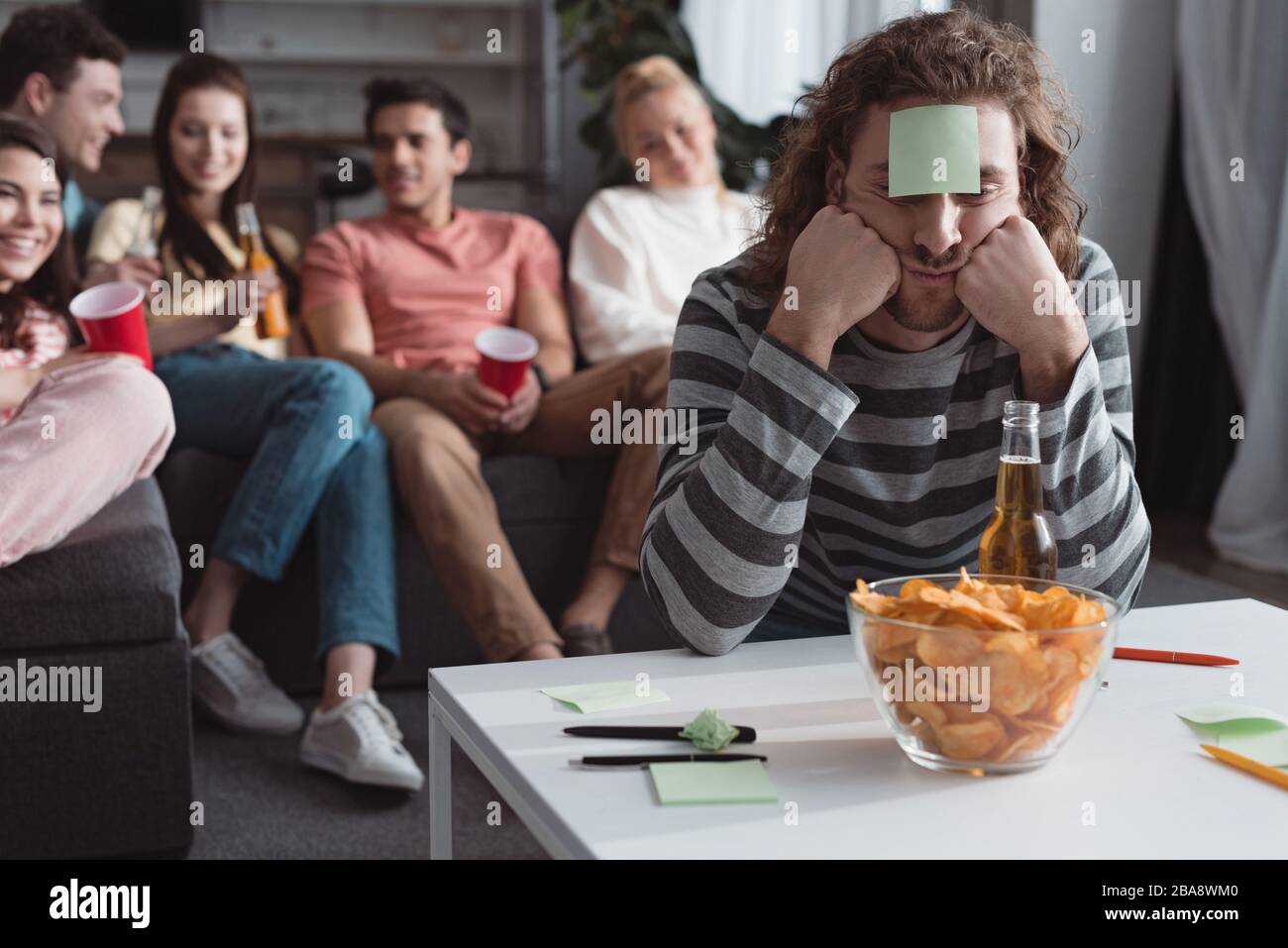 selective focus of bored man with sticky note on forehead playing name ...