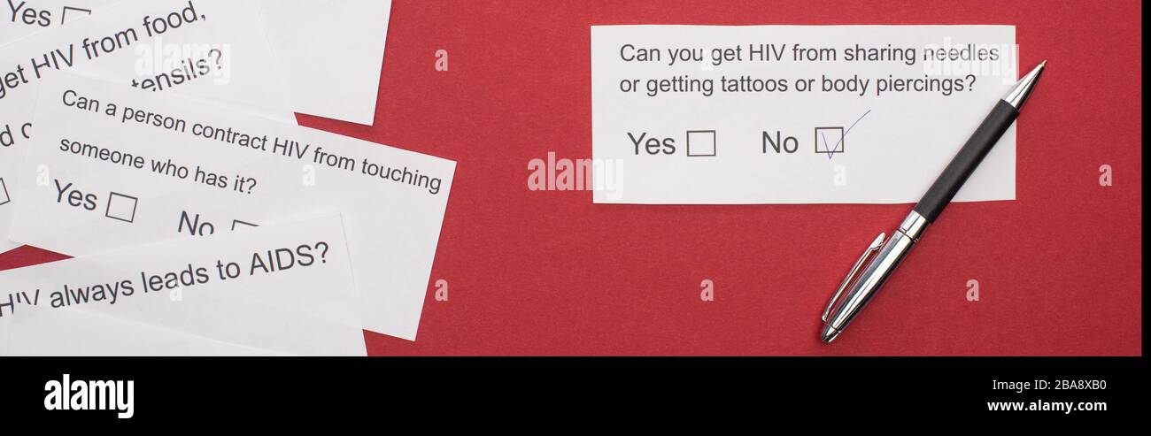 top view of paper cards with HIV questionnaire and pen on red ...