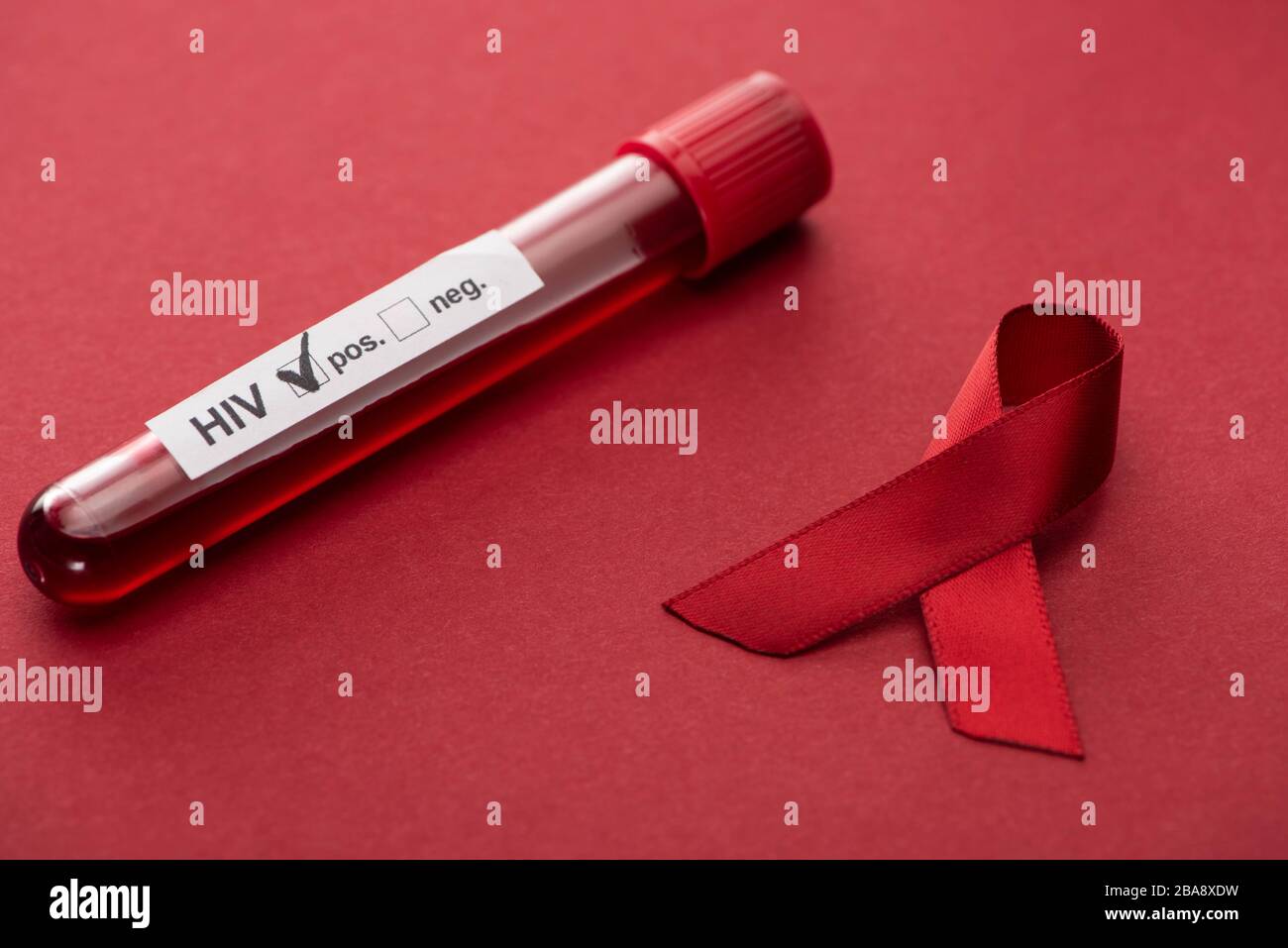 red awareness aids ribbon and positive hiv blood sample test on red ...