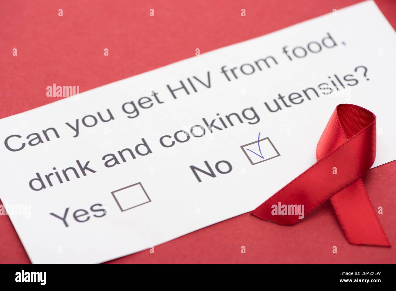 paper card with HIV questionnaire with awareness ribbon on red ...