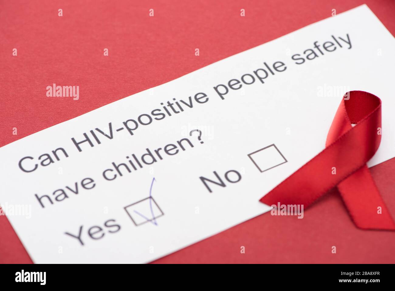 paper card with HIV questionnaire with awareness ribbon on red ...