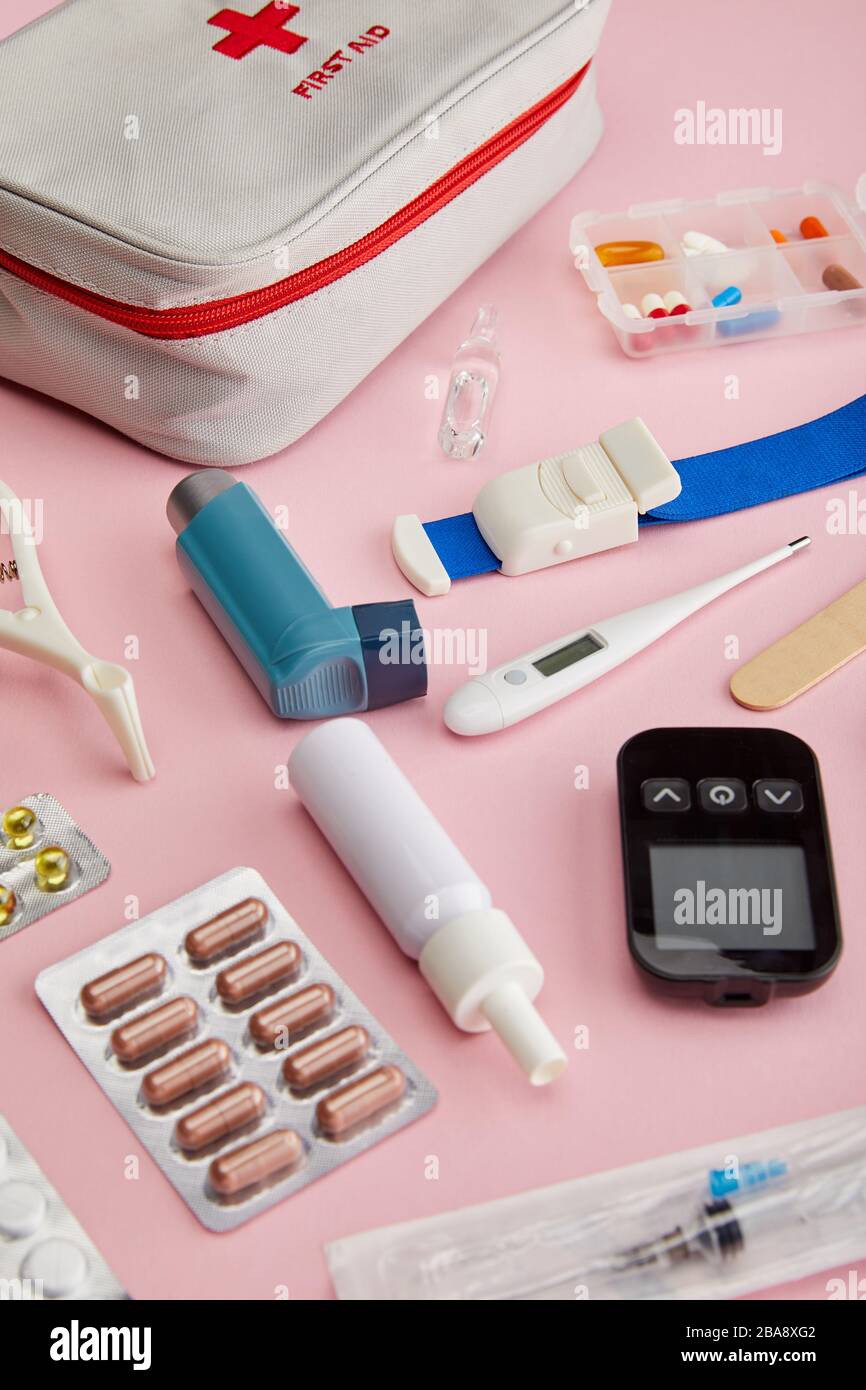 High angle view of first aid kit near medical objects on pink ...