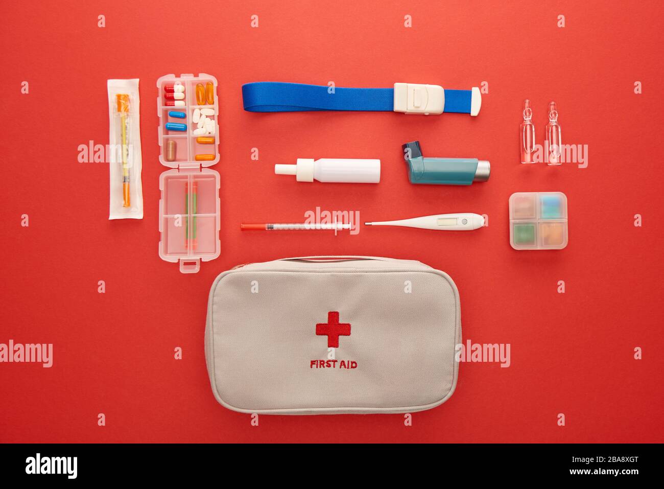 Flat lay with first aid kit, pills and medical objects on red ...