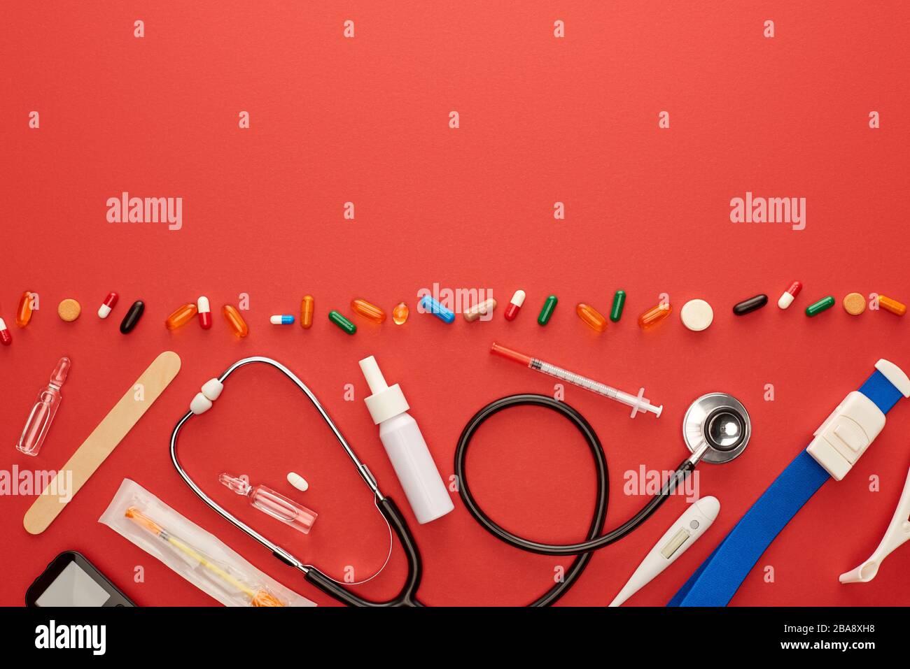 Top view of colorful medicines with medical objects on red background ...